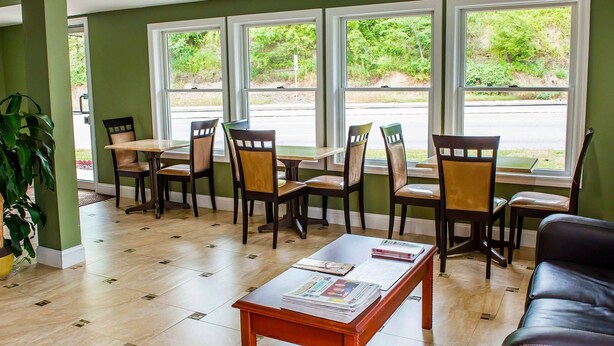Uma sala de jantar com mesa e cadeiras, janelas amplas com vista para áreas verdes, e piso revestido com azulejos.