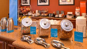Uma área de buffet com diversas opções de comida e utensílios.