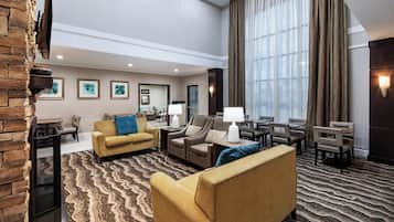 Um saguão de hotel com lareira, área de estar e grandes janelas.