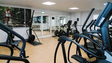 Academia com esteiras, bicicletas ergométricas e remo.