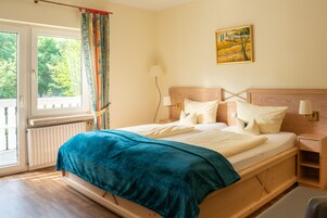 Quarto com cama, janela com cortinas, quadro na parede e mesa de cabeceira com abajur.