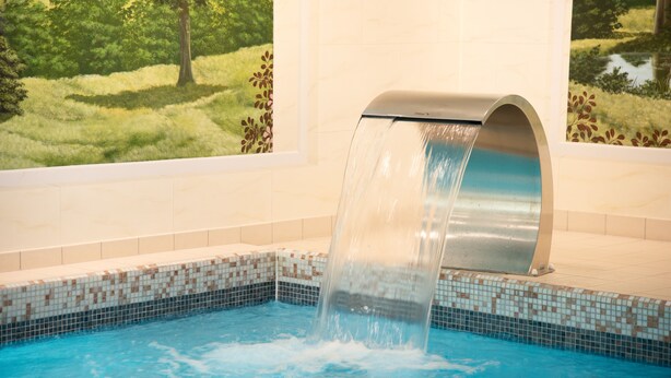 Piscina com cascata e azulejos decorativos.