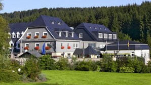 Um edifício grande, com vários andares, fachada simétrica, diversas janelas e entrada destacada.