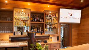 Uma área de bar com prateleiras de garrafas de bebidas, uma máquina de café e um letreiro para Landhaus Wacker.