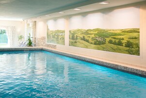 Piscina com um mural de uma paisagem verde na parede.