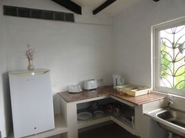 Uma cozinha compacta com geladeira, torradeira, chaleira e pia.
