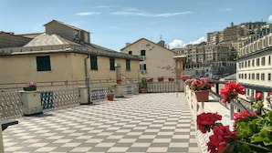Terraço no telhado com piso xadrez, plantas em vasos e guarda-corpo.