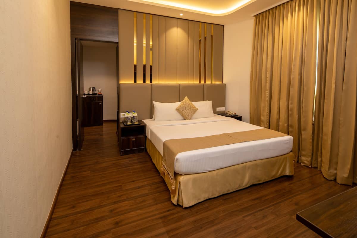 Quarto de hotel com uma cama grande, mesa de cabeceira, armário e espelho.
