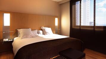 Quarto de hotel moderno com uma cama grande, mesas de cabeceira e uma janela com cortinas.