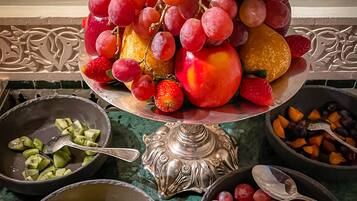 Exposição de frutas com diversas variedades, incluindo uvas, pêssegos e morangos.