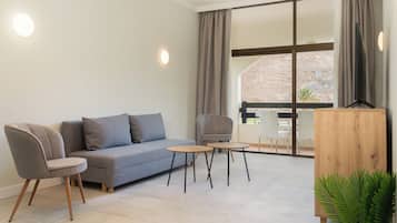 Uma sala de estar moderna com um sofá cinzento, duas poltronas, uma mesa de centro e um aparador de madeira.