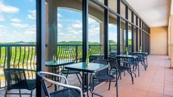 Terraço com área de estar ao ar livre, grandes janelas e vista para a paisagem.