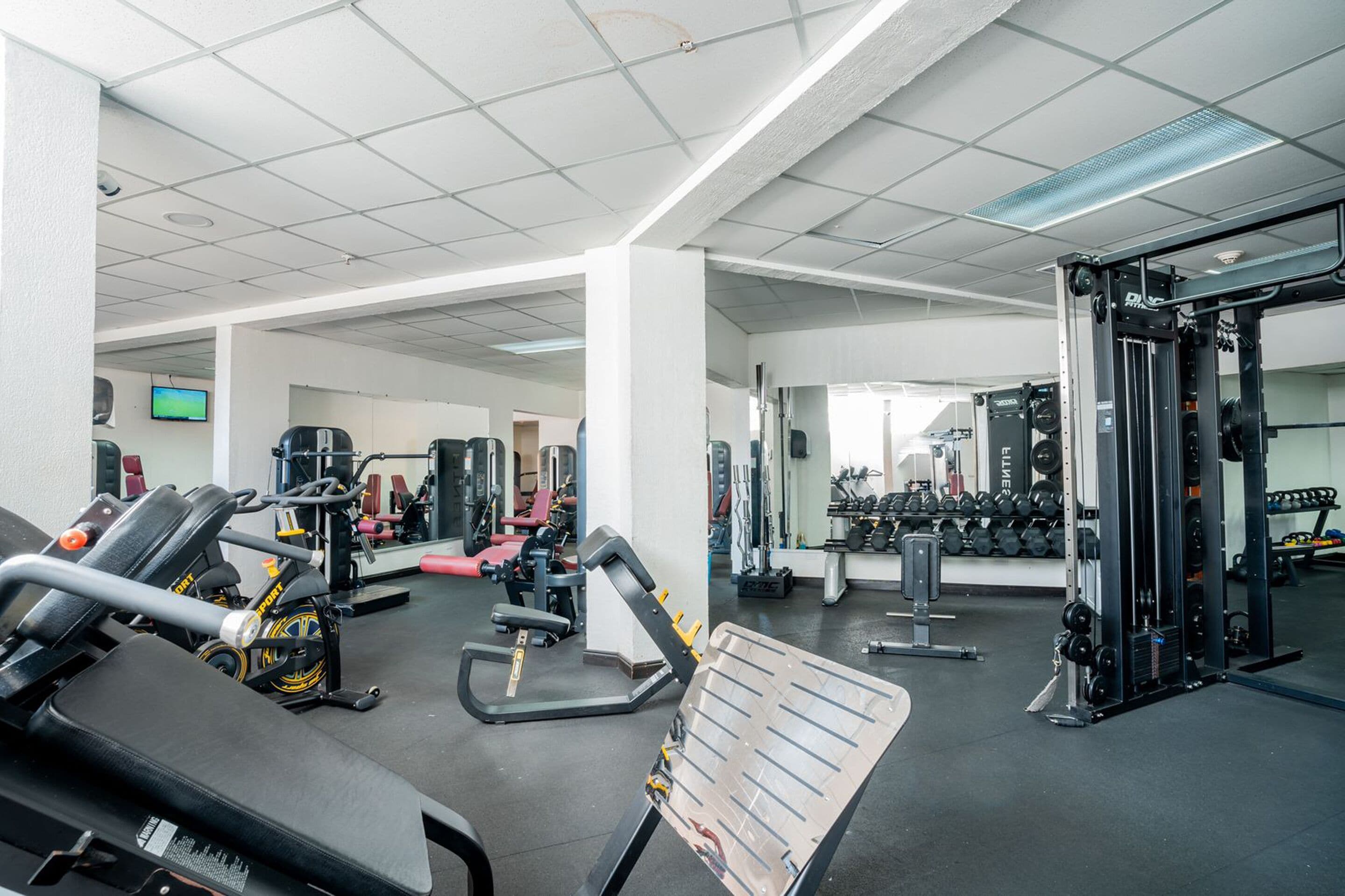 Uma academia com diversos equipamentos de exercícios, incluindo esteiras e aparelhos de musculação.