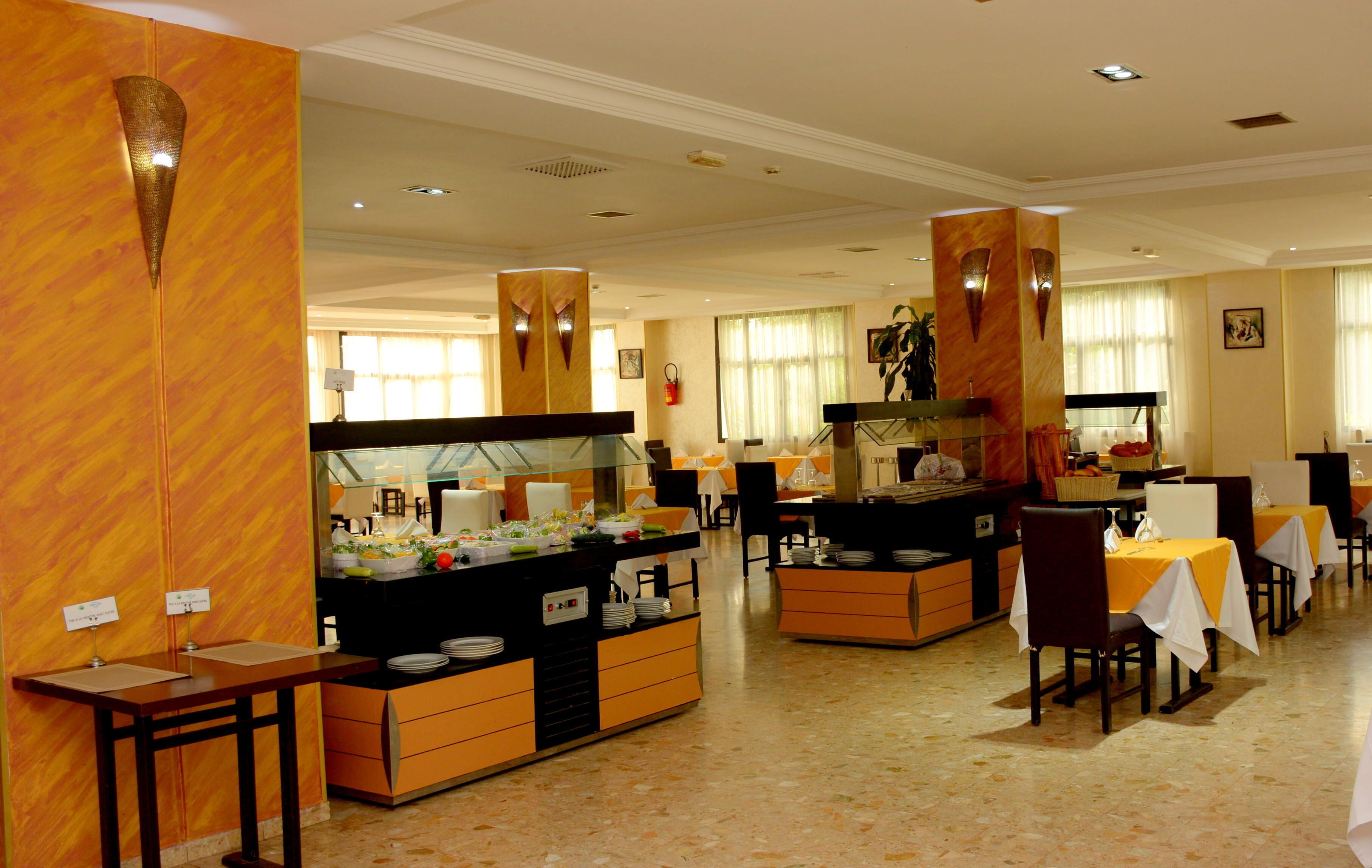 Um saguão de hotel com área de buffet, disposição de assentos e balcão de recepção.