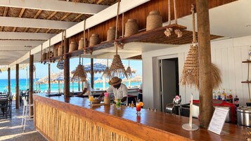 Uma área de bar com balcão de madeira, garrafas e um suporte para o cardápio.