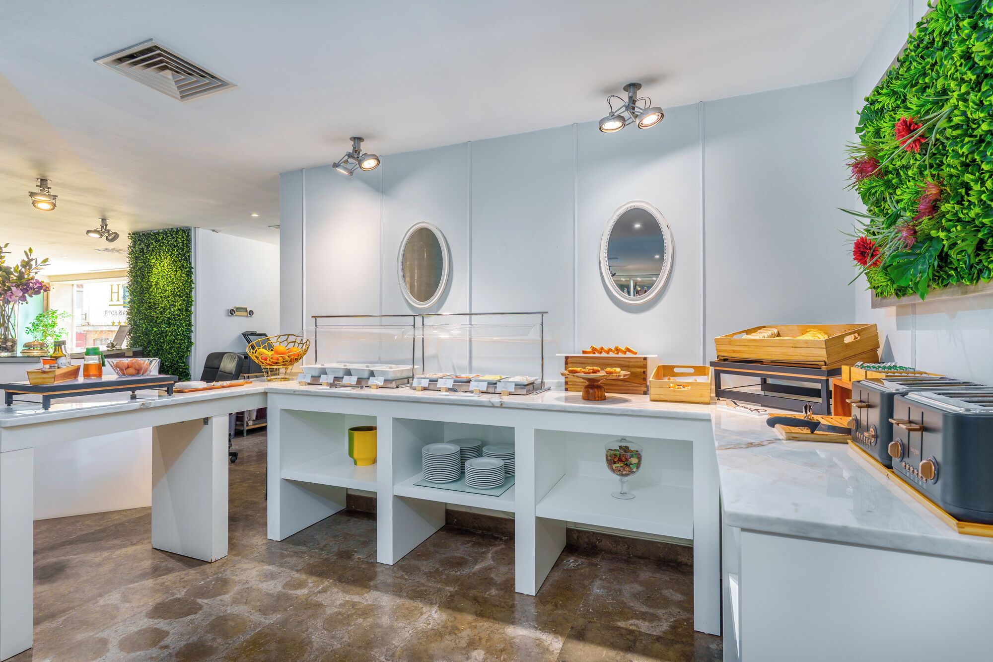 Uma zona de pequenos-almoços moderna com serviço de buffet, incluindo diversas opções de comida e uma estação de café.