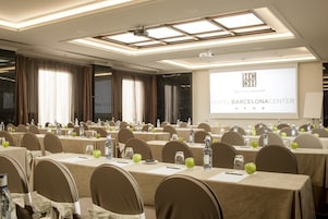 Sala de conferência com mesas preparadas para uma reunião, equipada com garrafas de água, copos e cadernos.