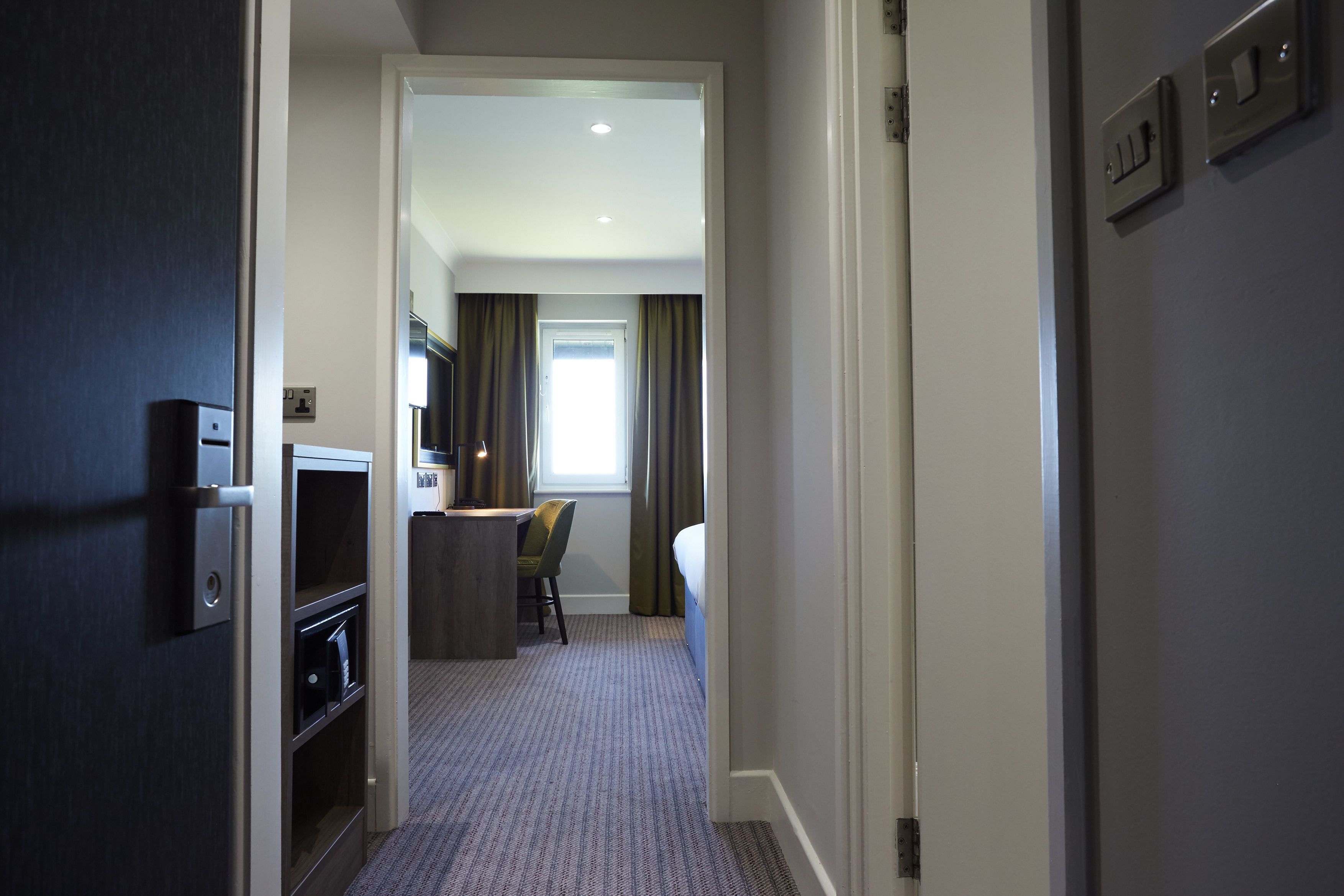 Quarto de hotel com cozinha compacta, escrivaninha e cama.