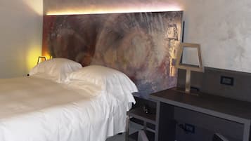 Quarto de hotel moderno com uma cama grande, uma mesa de escritório e uma obra de arte abstrata original na parede.