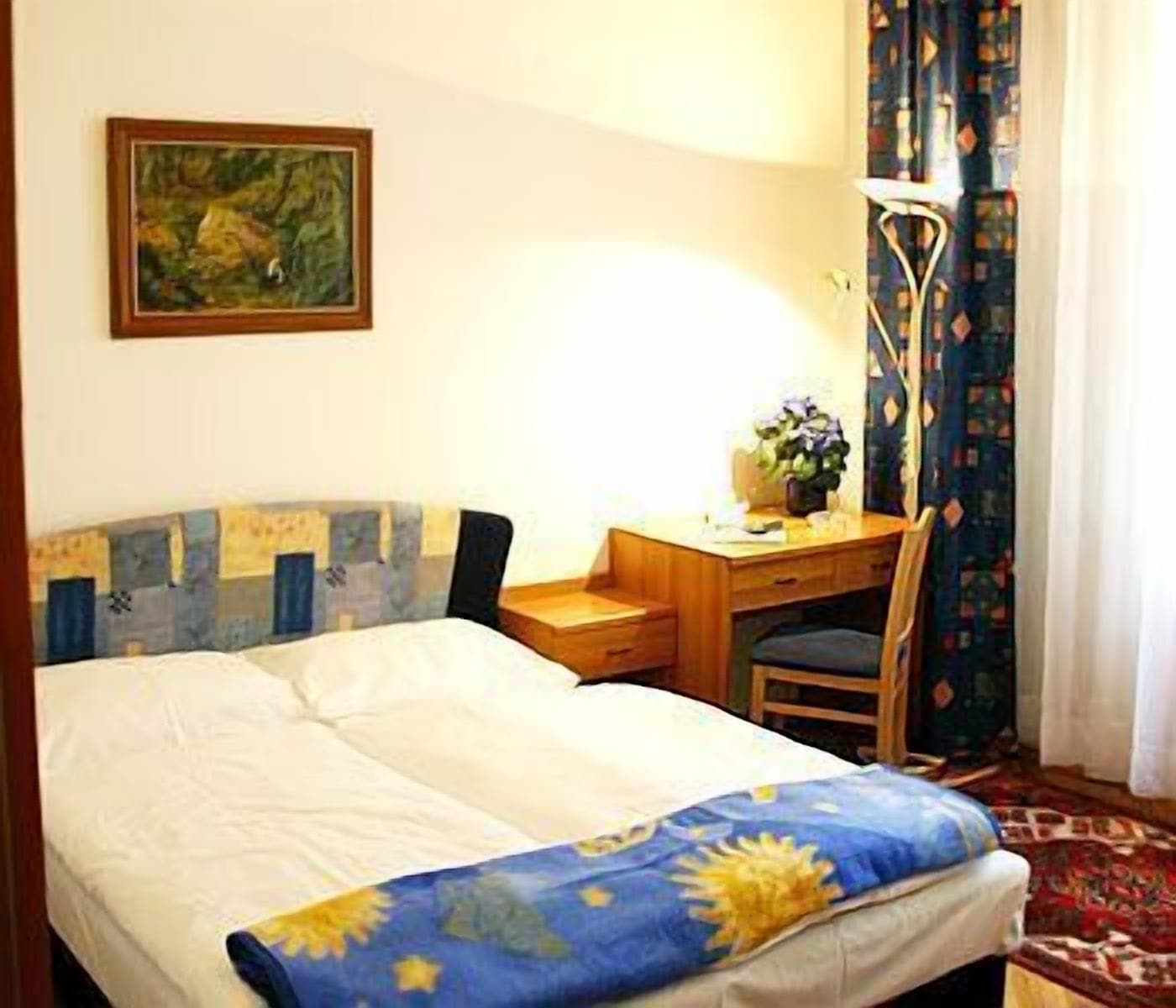 Quarto de hotel com cama, escrivaninha e cadeira.
