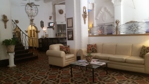 Sala de estar com sofá, poltronas, mesa de centro e piso estampado.