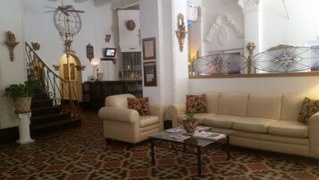 Sala de estar com sofá, poltronas, mesa de centro e piso estampado.