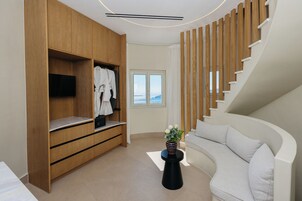 Um interior moderno com um guarda-roupa de madeira, um sofá, uma escada e vista para o mar.