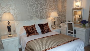 Quarto bem arrumado com uma cama grande, duas mesas de cabeceira com luminárias, cômoda e espelho.