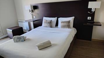 Quarto de hotel com uma cama grande, duas mesas de cabeceira, uma escrivaninha e uma cadeira.
