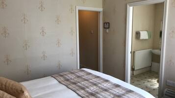 Quarto com cama, radiador e banheiro visível por uma porta aberta.