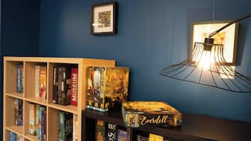 Uma estante com vários jogos de tabuleiro e um quadro na parede.