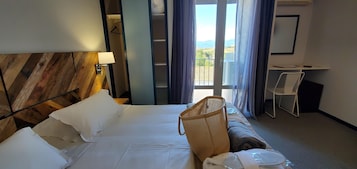 Quarto de hotel com cama, escrivaninha, cadeira e vista para o exterior.