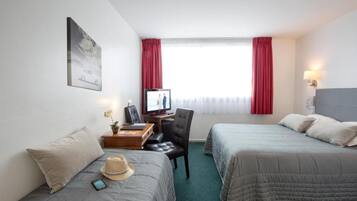 Quarto de hotel com duas camas, uma escrivaninha com computador, uma cadeira e janela com cortinas.