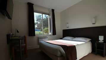Quarto com cama, escrivaninha com cadeira, janela com cortinas e mesa de cabeceira com abajur.