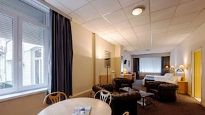 Quarto de hotel com área de refeições, cama e banheiro.
