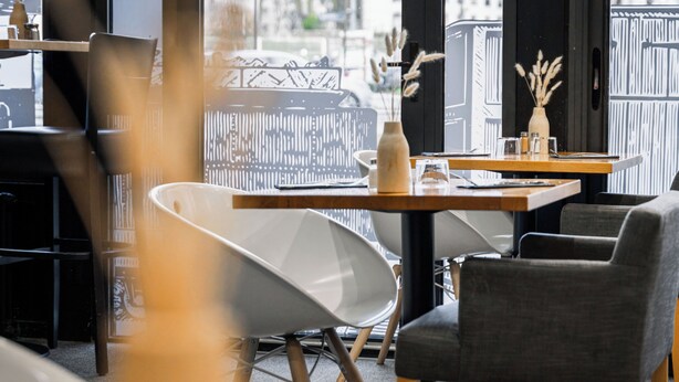 Um interior moderno com uma sala de jantar com uma mesa de madeira, uma cadeira branca e uma poltrona escura.