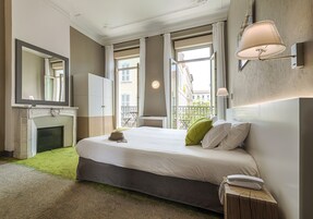 Quarto de hotel moderno com uma cama grande, lareira, espelho e vista para a varanda.