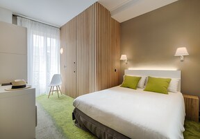 Quarto de hotel moderno com uma cama grande, uma escrivaninha e uma cadeira.