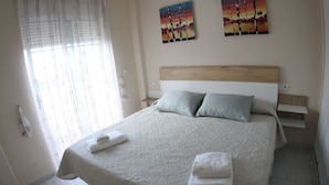Quarto com uma cama grande, duas almofadas, uma cabeceira de madeira e duas pinturas penduradas na parede.