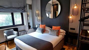 Quarto moderno com uma cama grande, um espelho redondo e vista para o exterior.