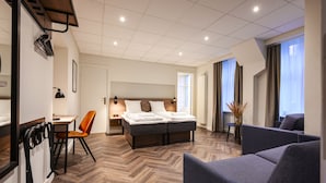 Quarto de hotel moderno com uma cama grande, uma escrivaninha e uma área de estar.