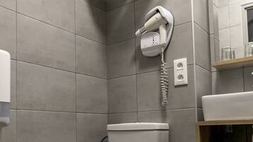 Um banheiro moderno com vaso sanitário, secador de cabelo e porta-toalhas.