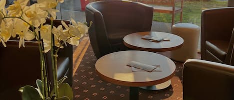 Uma área de estar moderna com assentos confortáveis, uma mesa de centro e vista para o exterior.
