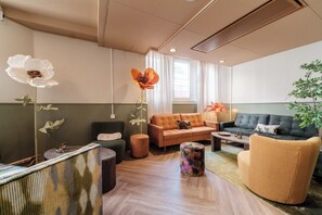 A modern living room with a sofa, armchairs, a coffee table, and a decorative vase with flowers.