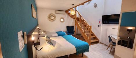 Quarto com cama, escrivaninha, cadeira, escada e televisão.