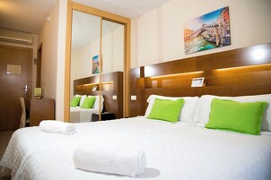 Quarto de hotel com uma cama grande, um espelho, cabeceira de madeira e um quadro de uma ponte.