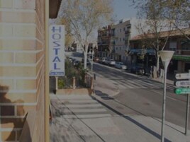 Vista da rua com um edifício com a placa 'HOSTAL' à esquerda.