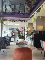 Um interior moderno com balcão de recepção, área de estar e plantas decorativas.
