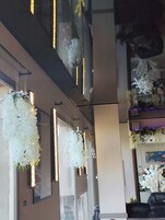 Um interior moderno com arranjos florais suspensos, uma poltrona de couro preto e uma janela grande.