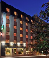 Um hotel com fachada moderna, várias varandas e janelas iluminadas.